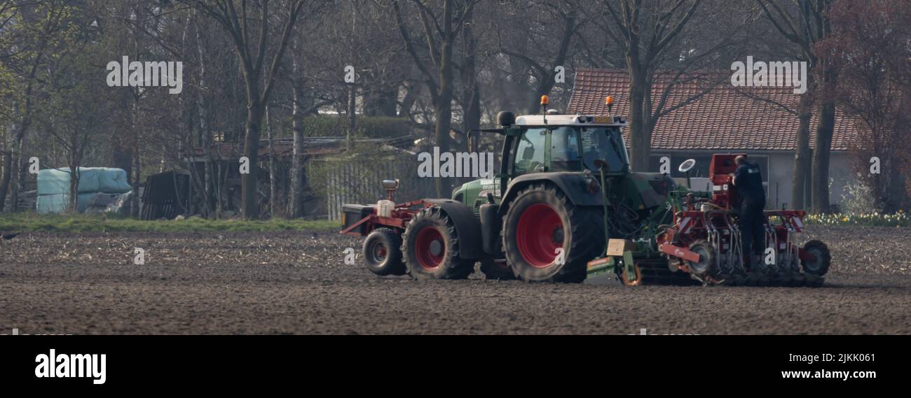 A Fendt tractor plowing in a field with a man putting maintenance work ...