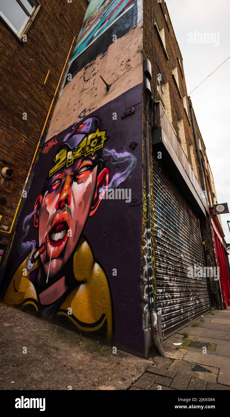 A low angle of graffiti of a smoking man on the wall of an old building ...