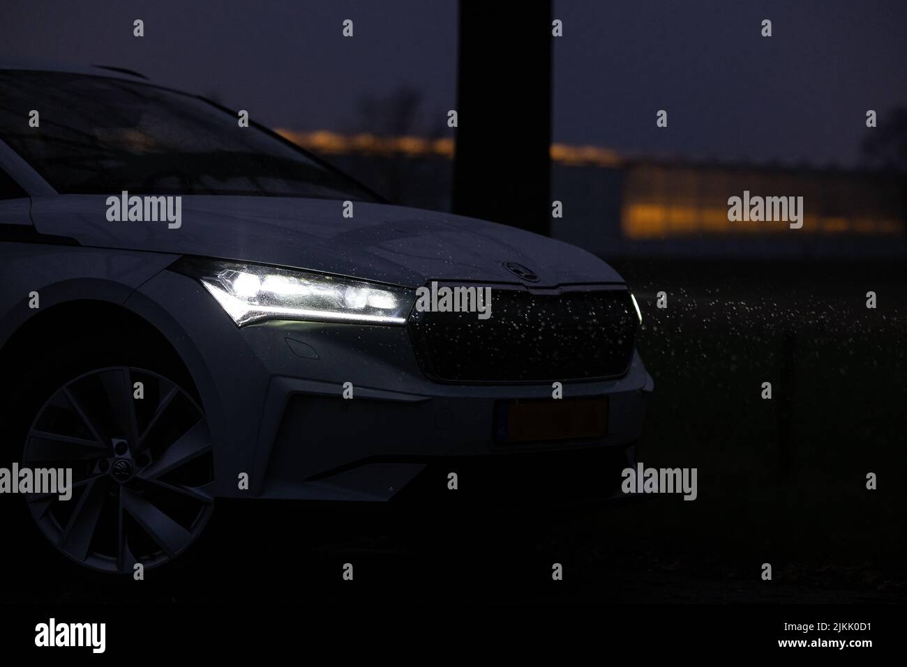 A closeup of a Skoda Enyaq front outside in the pouring rain at night ...