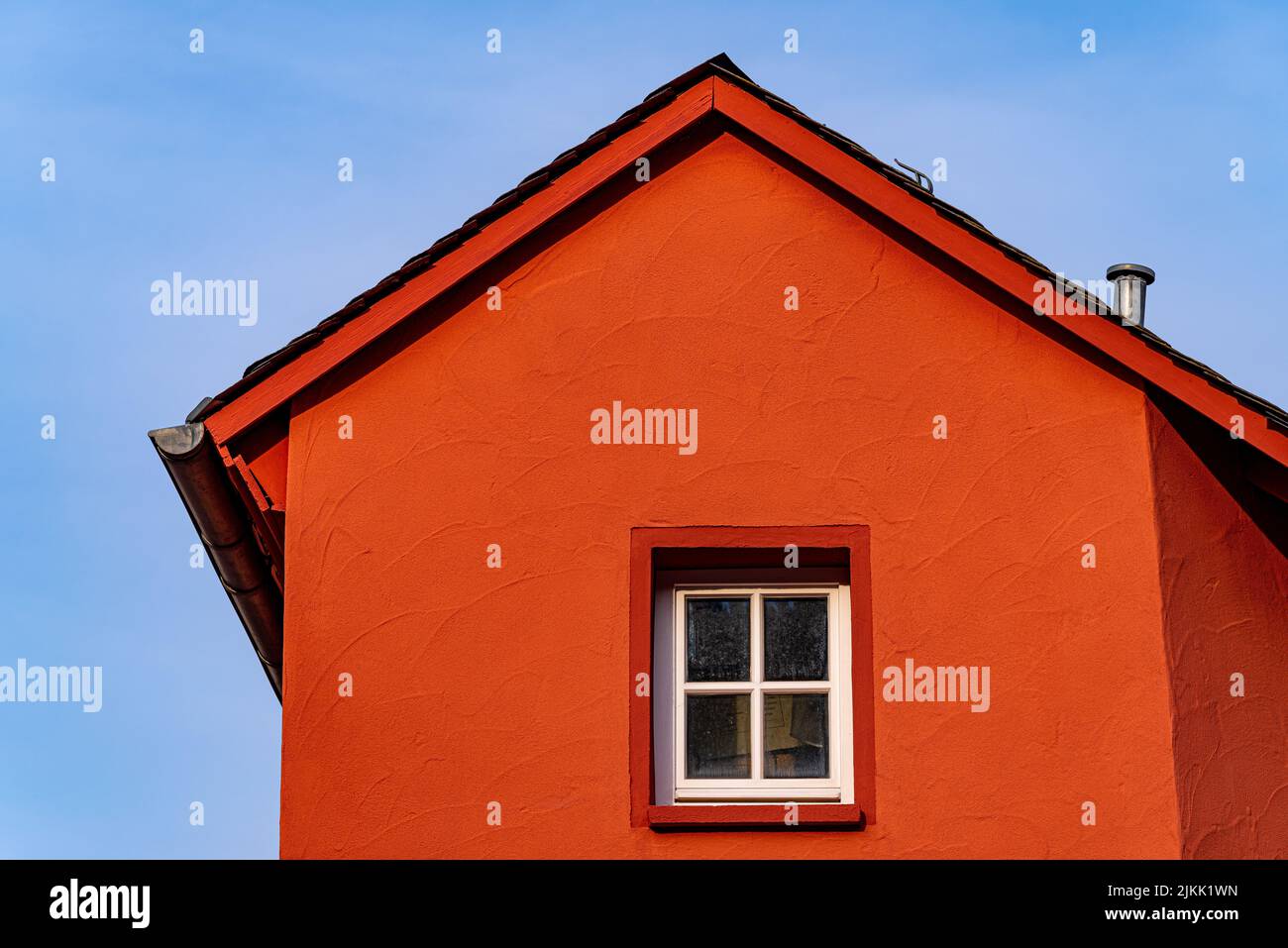A red stone building with a window on a blue sky background Stock Photo ...