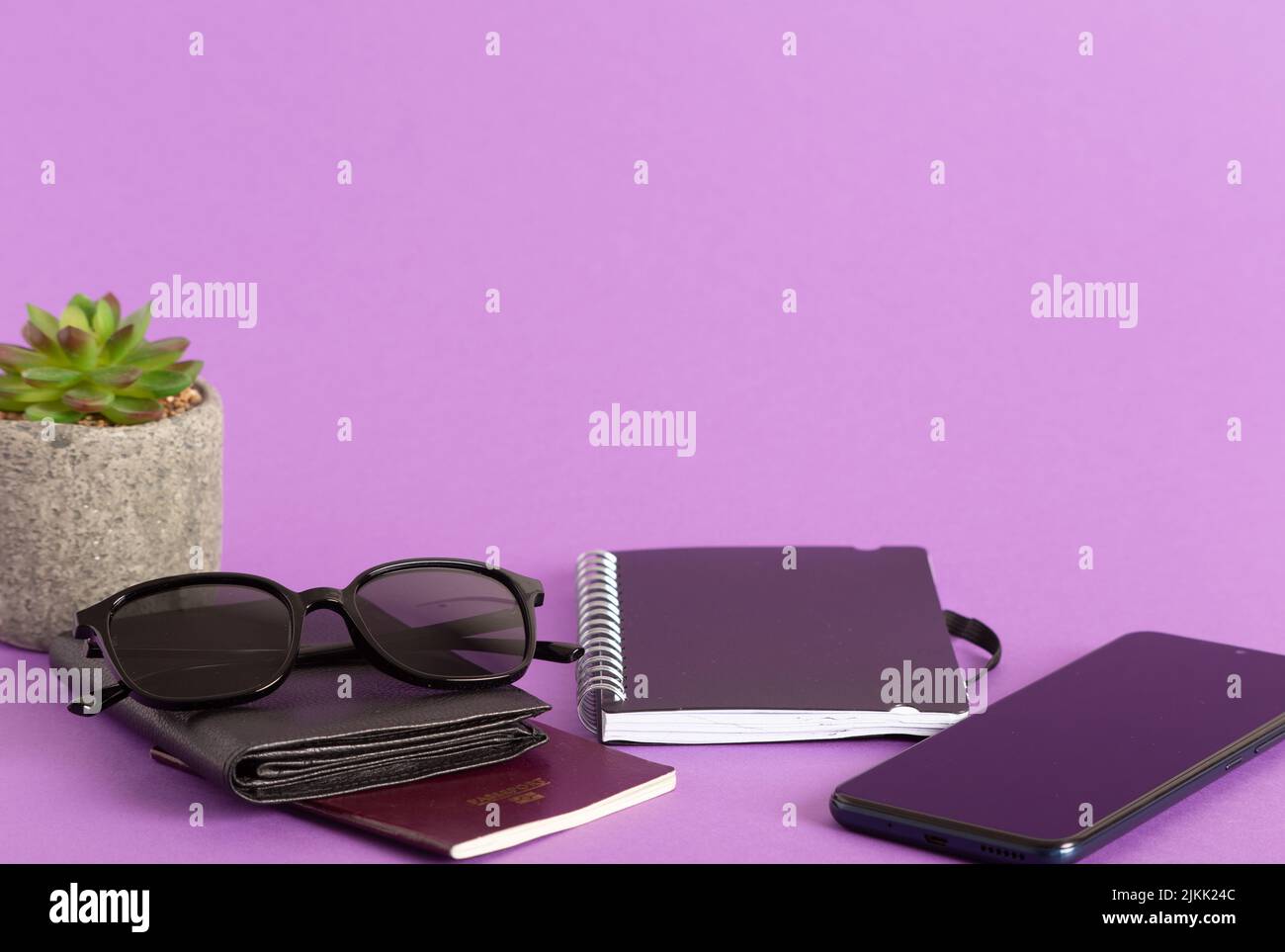 A closeup of a smartphone, sunglasses, notebooks and a wallet on a ...