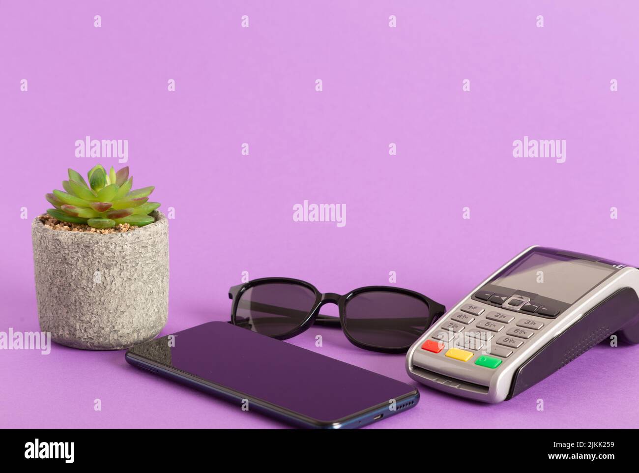 A wireless POS machine, a smartphone, sunglasses and houseplant on a ...