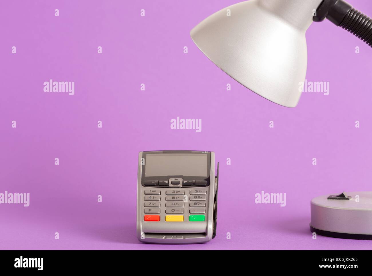 A wireless POS machine and lamp on a purple background Stock Photo - Alamy