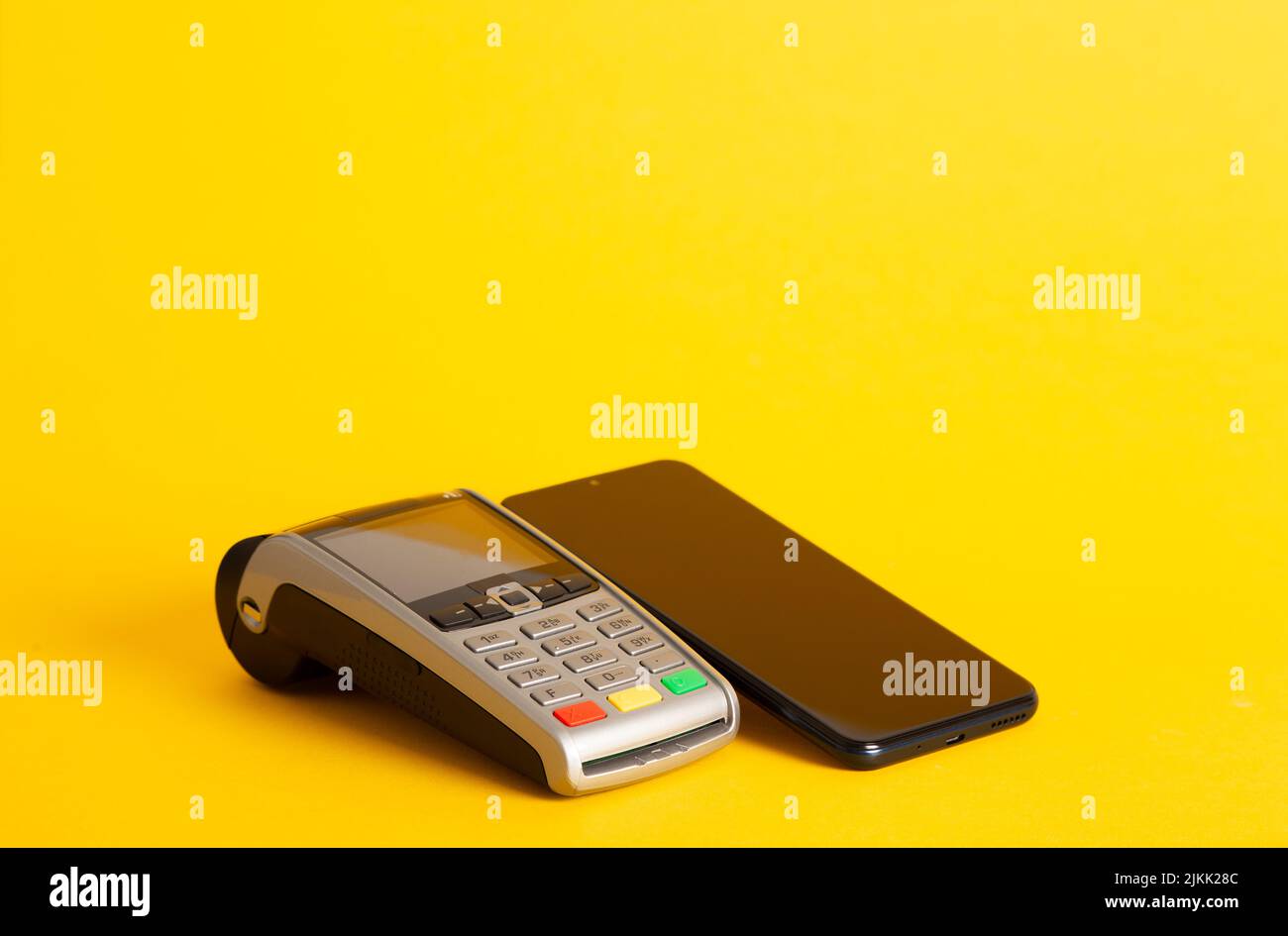 A closeup of a POS terminal and smartphone isolated on a yellow ...