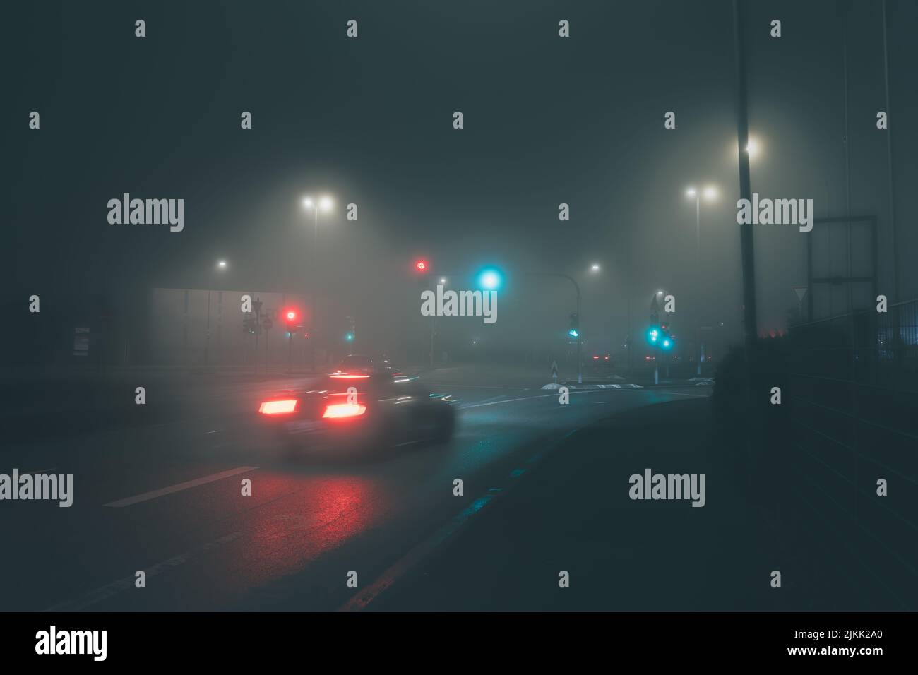 A view of a car driving in an empty street illuminated with lanterns at ...