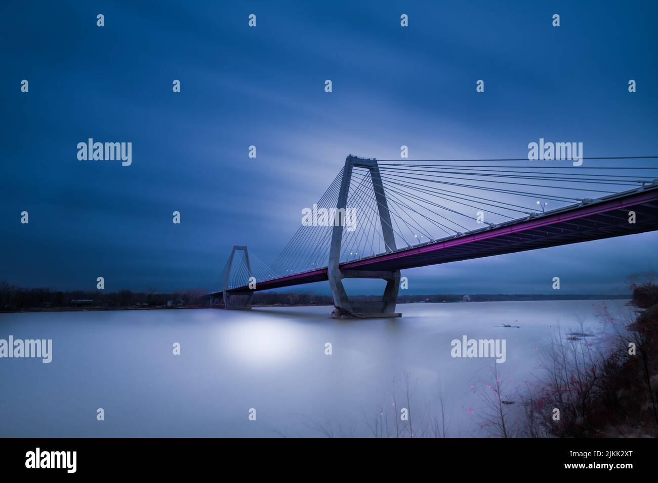 A Vertical shot of a bridge over the water during evening and a blue ...
