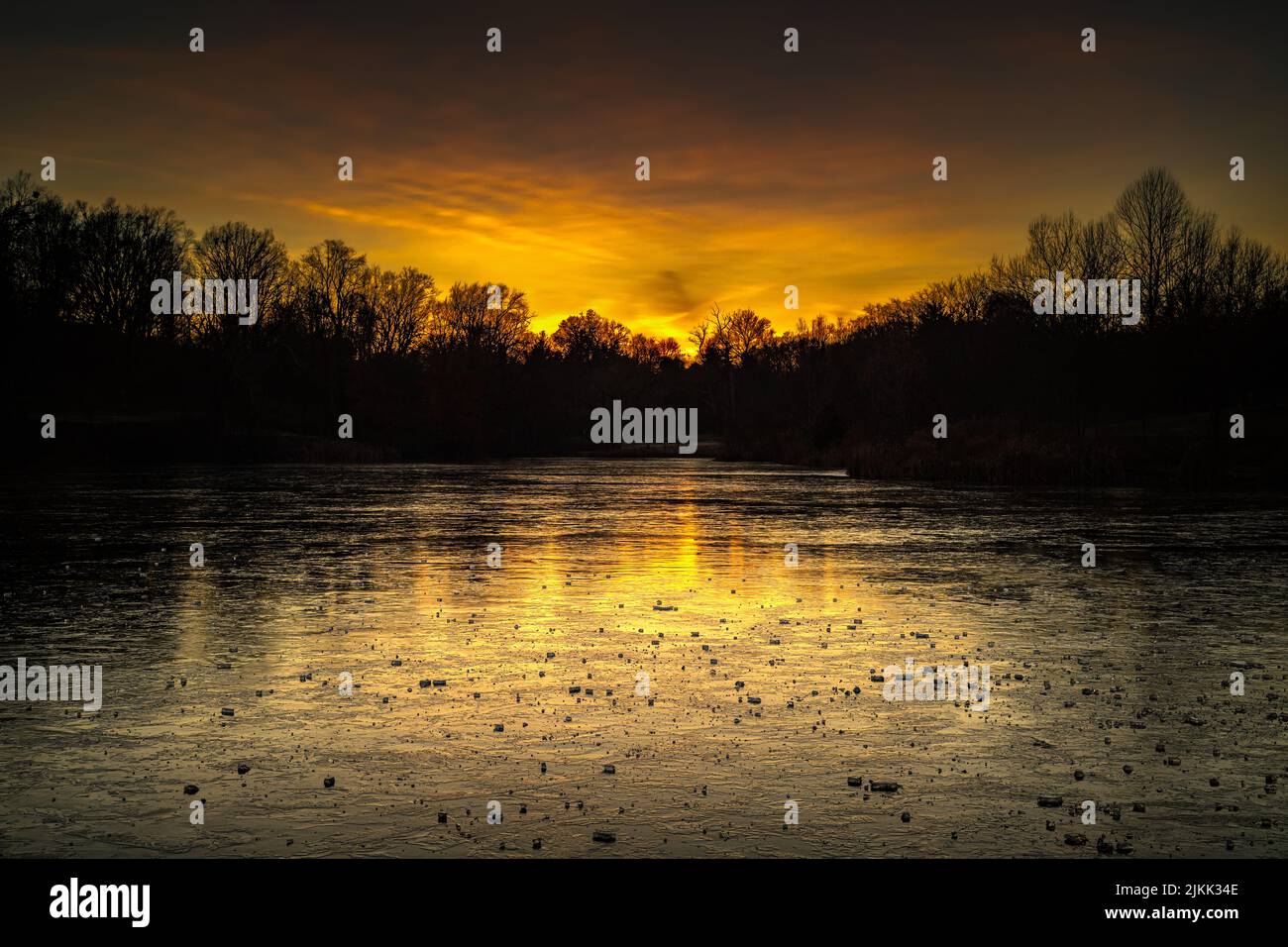 A gorgeous view of the Cherokee Lake during sunset with a frozen surface surrounded by dark ...