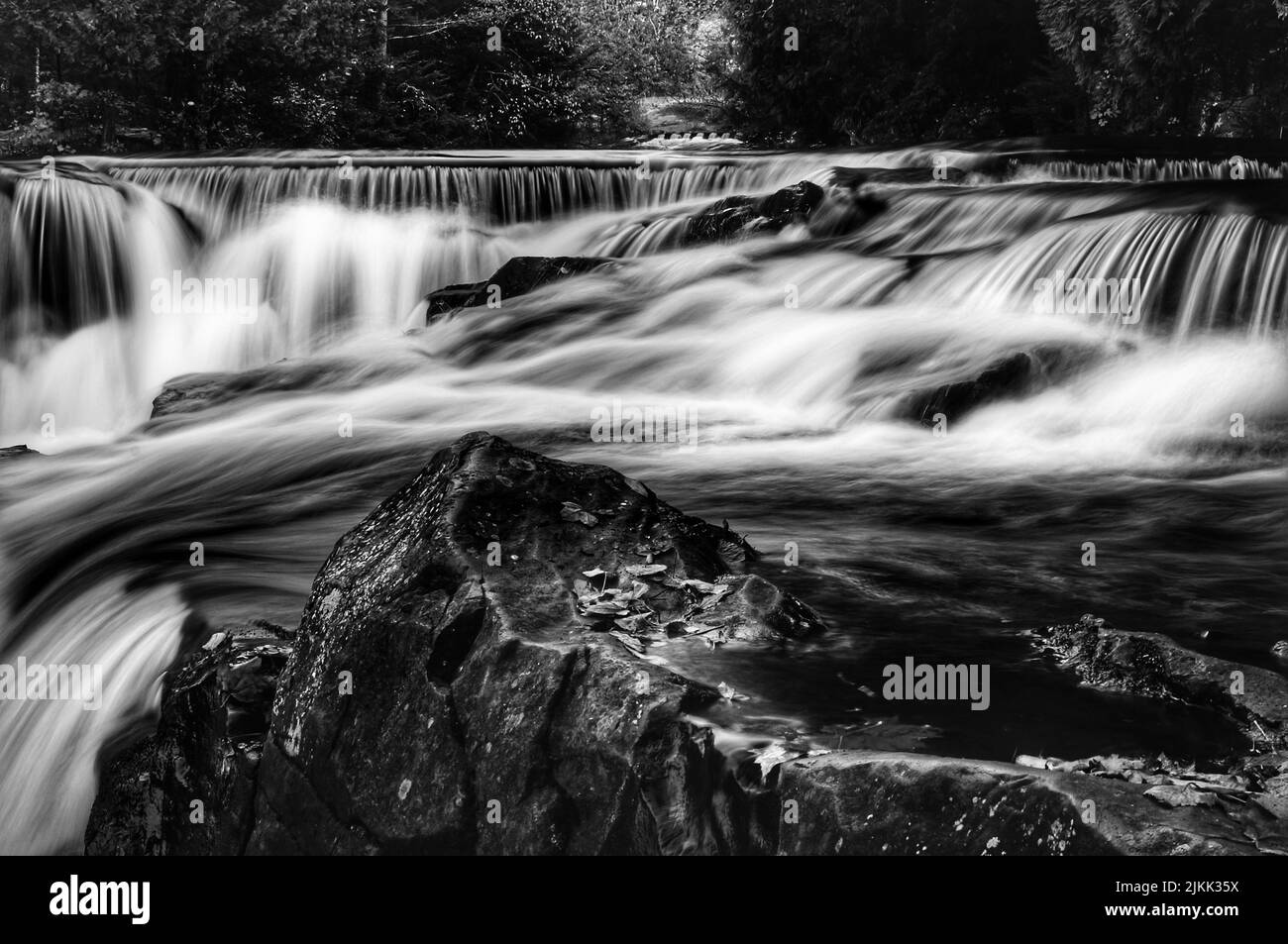 A grayscale shot landscape of waterfalls foam water flowing on rocks in ...