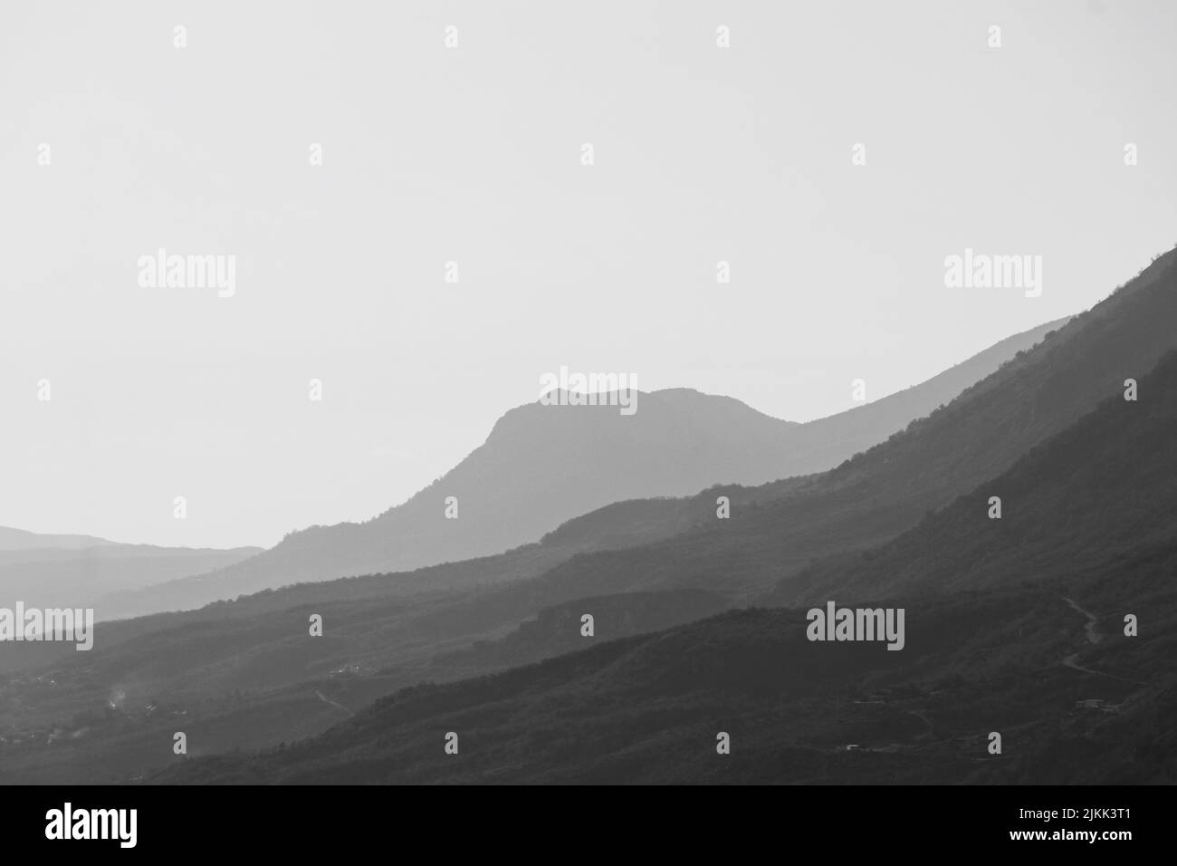 A grayscale shot of sand and mountains in the desert with foggy weather ...