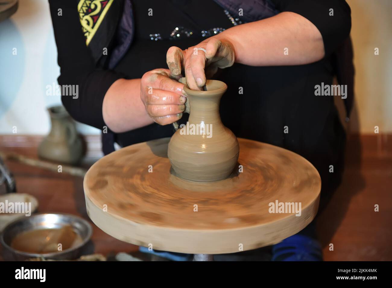 A woman's hands making a clay pot on a rotating potter's wheel. Potter ...