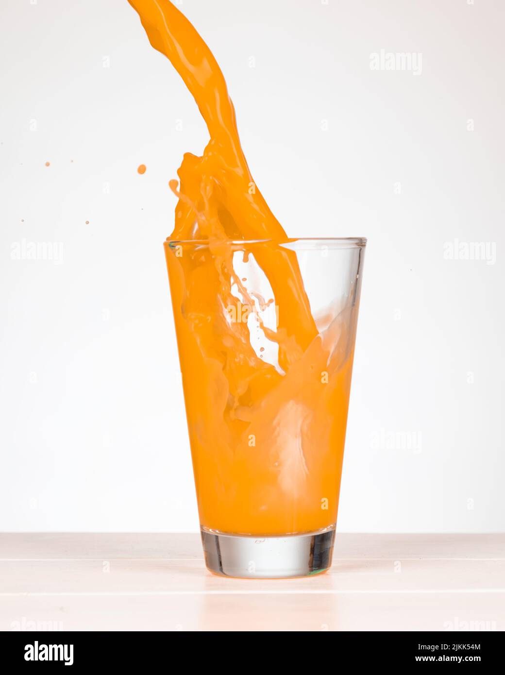 pour multivitamin juice in a glass with splashing Stock Photo - Alamy