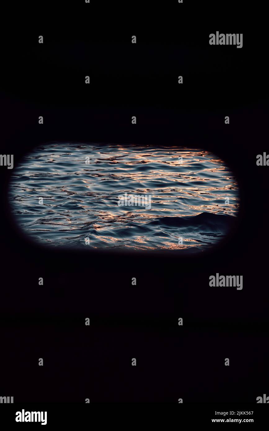 A vertical shot of the sea water seen from a whole on a black ...