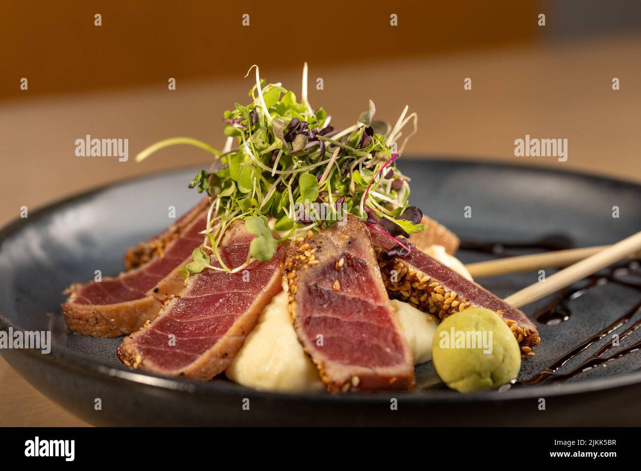 A portion of delicious fish tataki topped with fresh greens Stock Photo ...