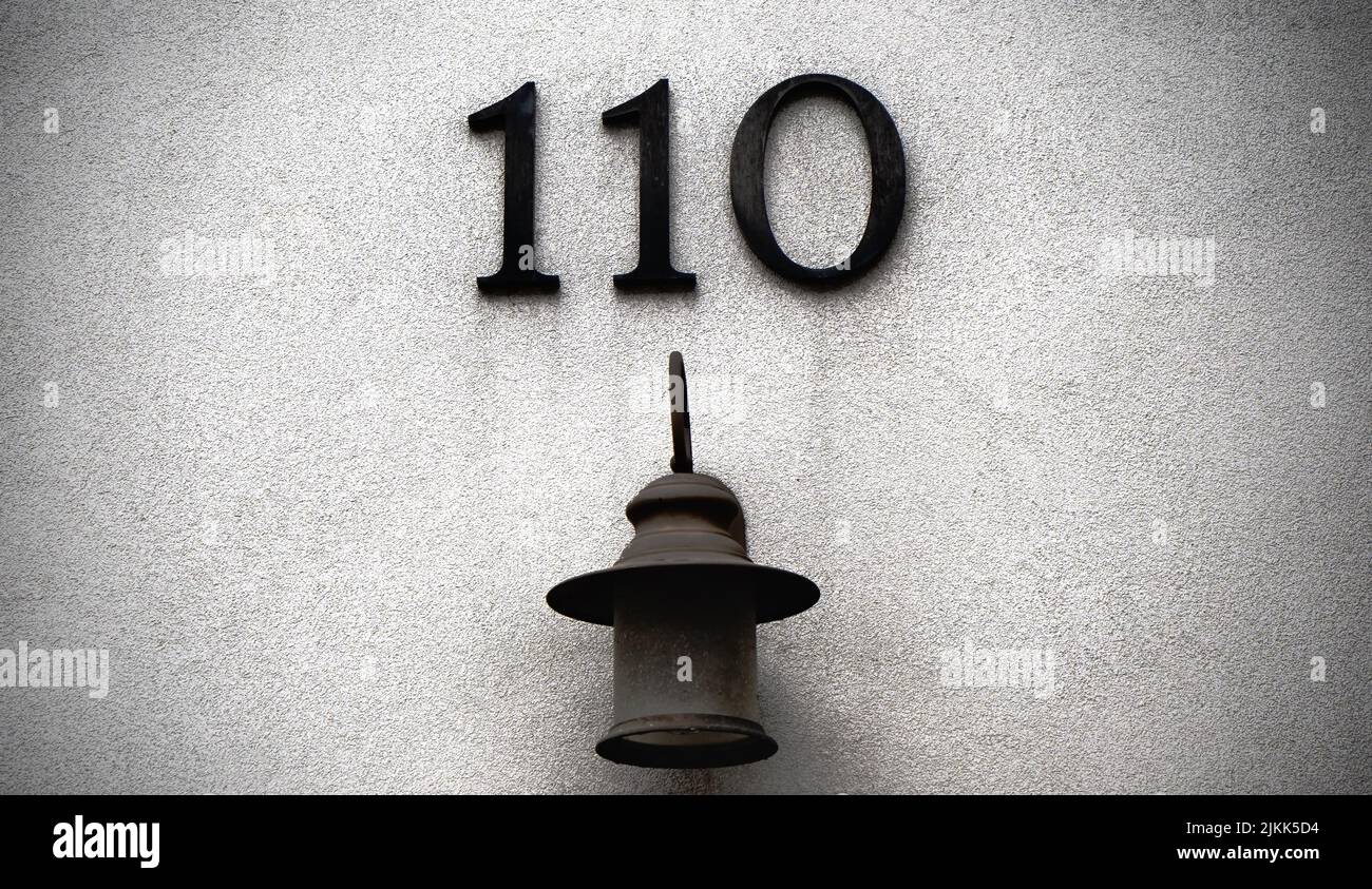 A closeup of the number 101 on the light gray wall with an old lamp ...