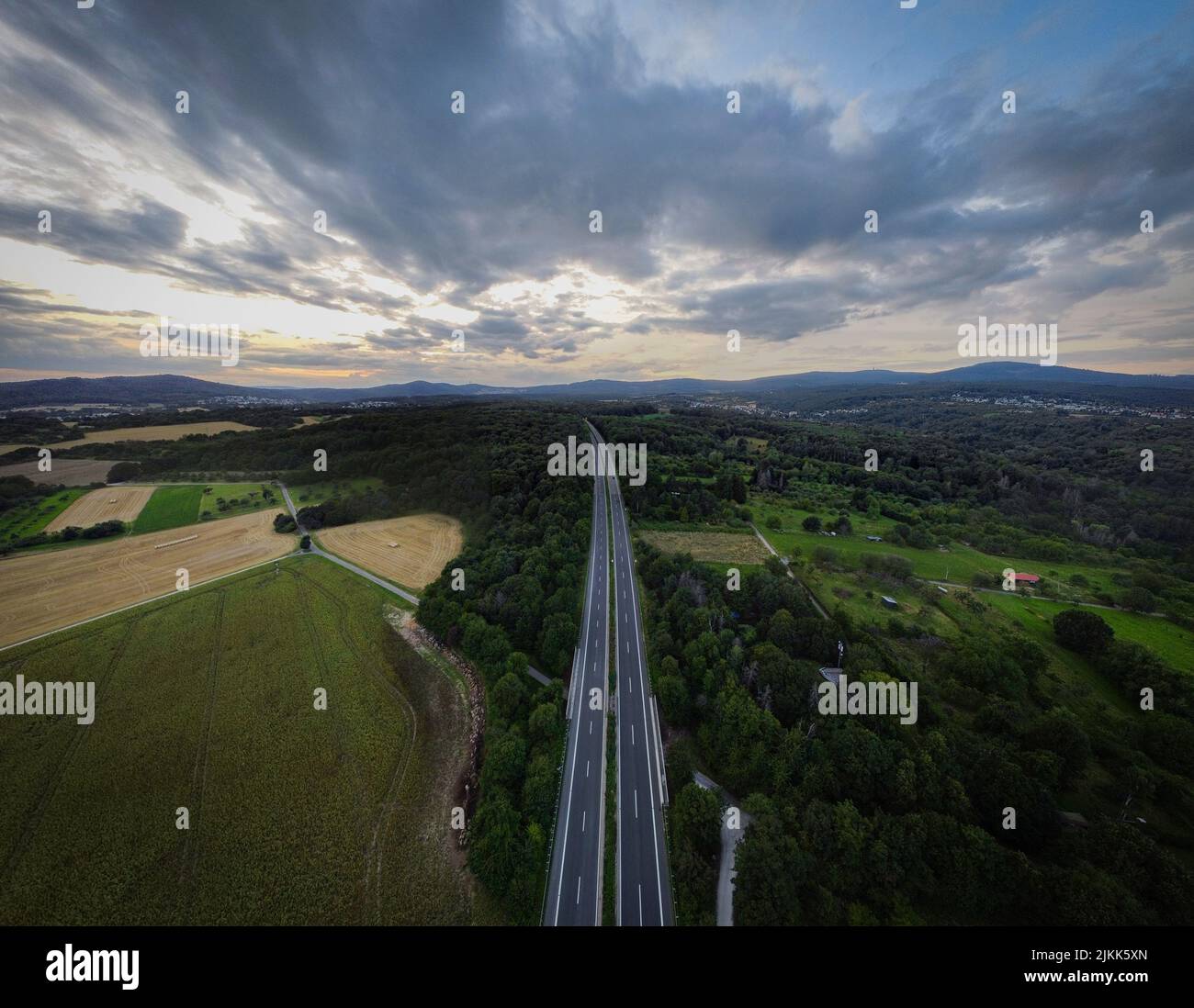 An aerial view of the long road going through the forests and the town ...