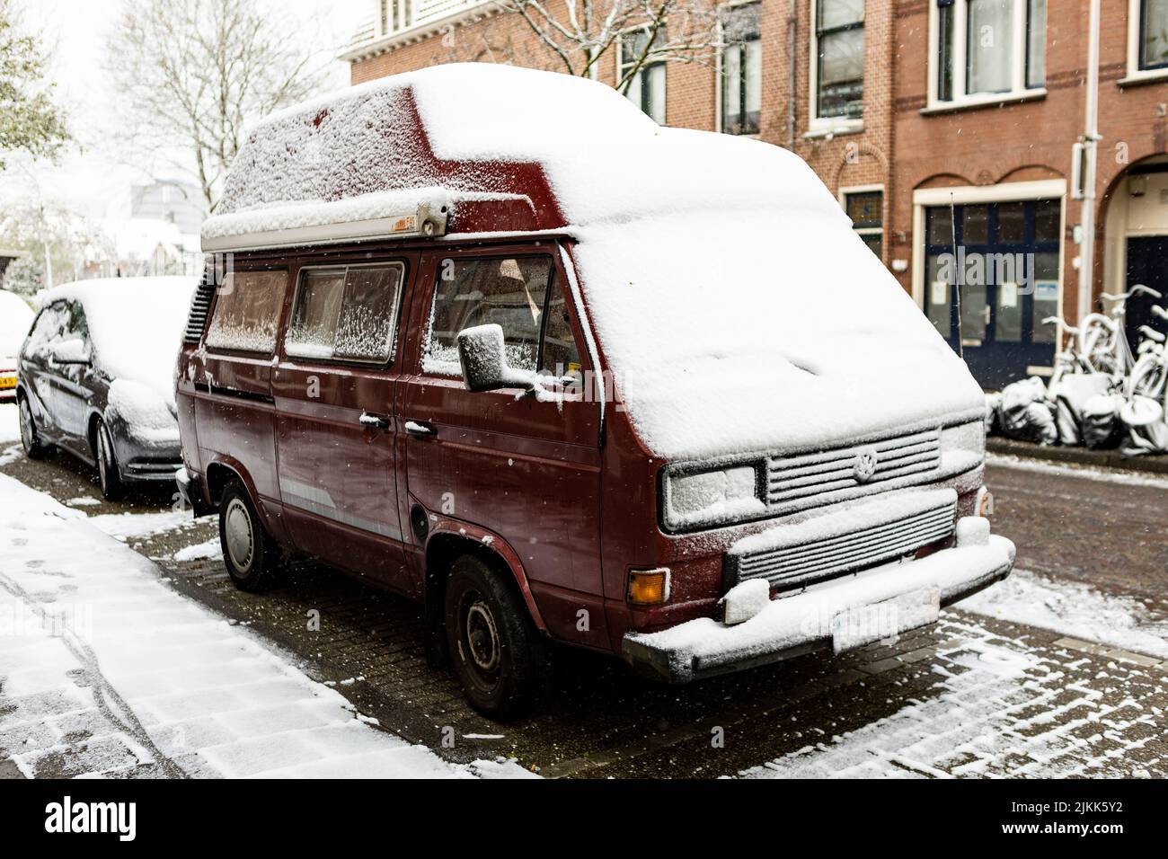 Parked dark red van covered in thick layer of snow in the streets of ...