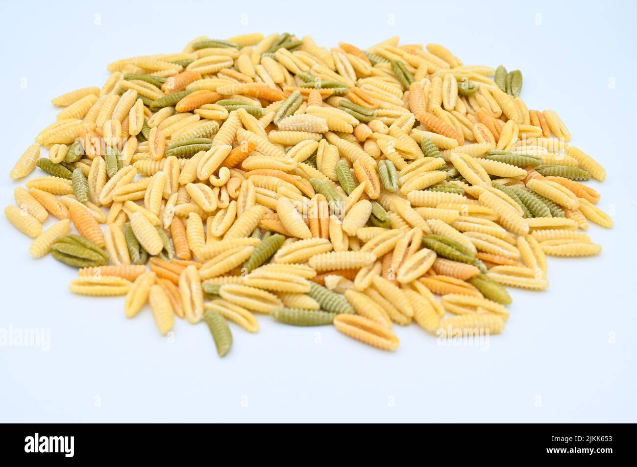 A closeup of colorful raw malloreddus pasta on a white surface Stock ...