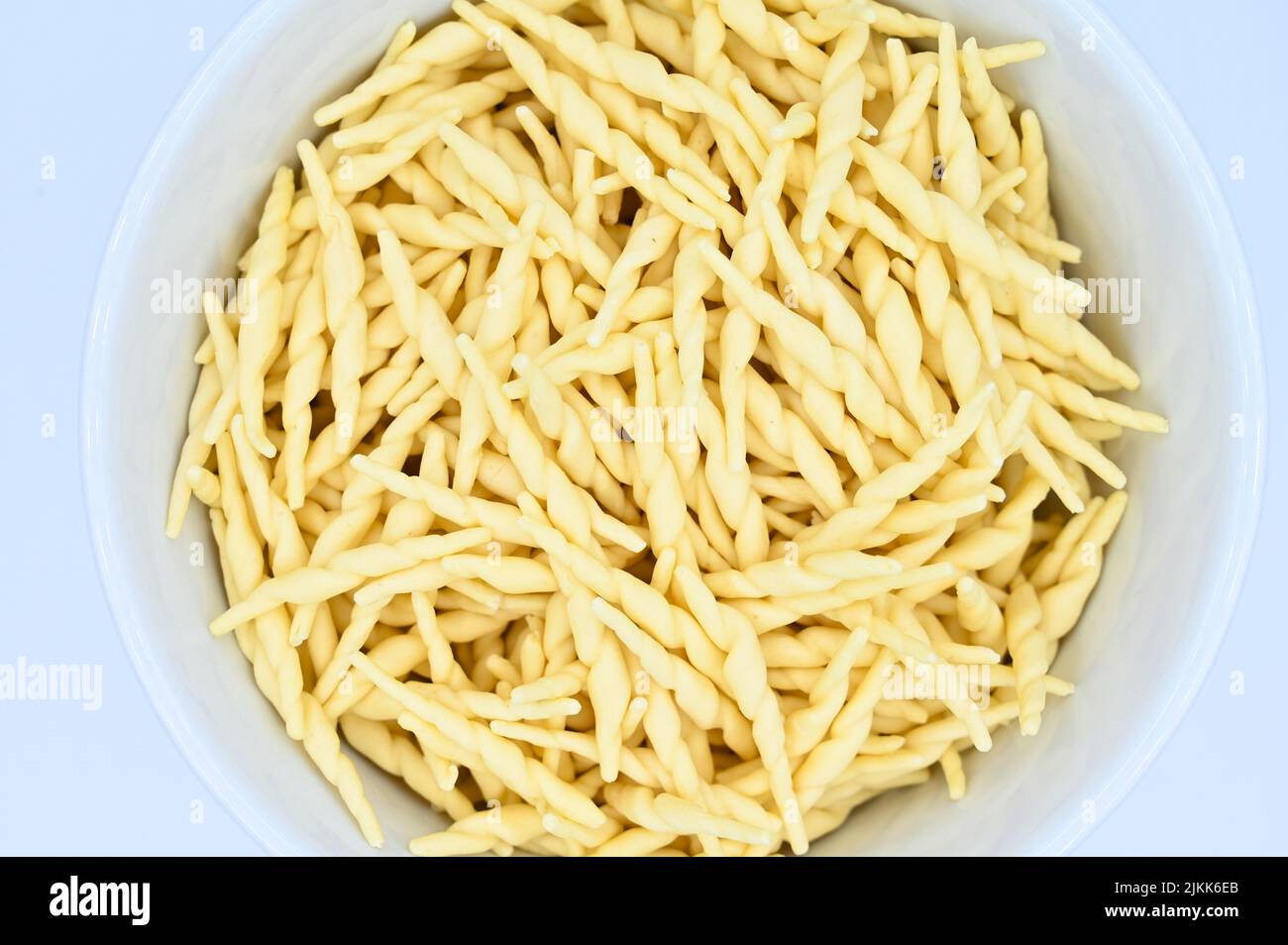 A top view of raw trofie pasta on a white background Stock Photo - Alamy