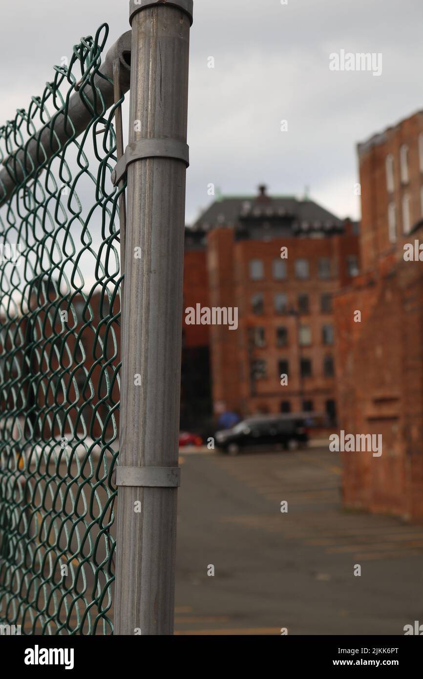 A vertical shot of a fence and red brick buildings in the background ...