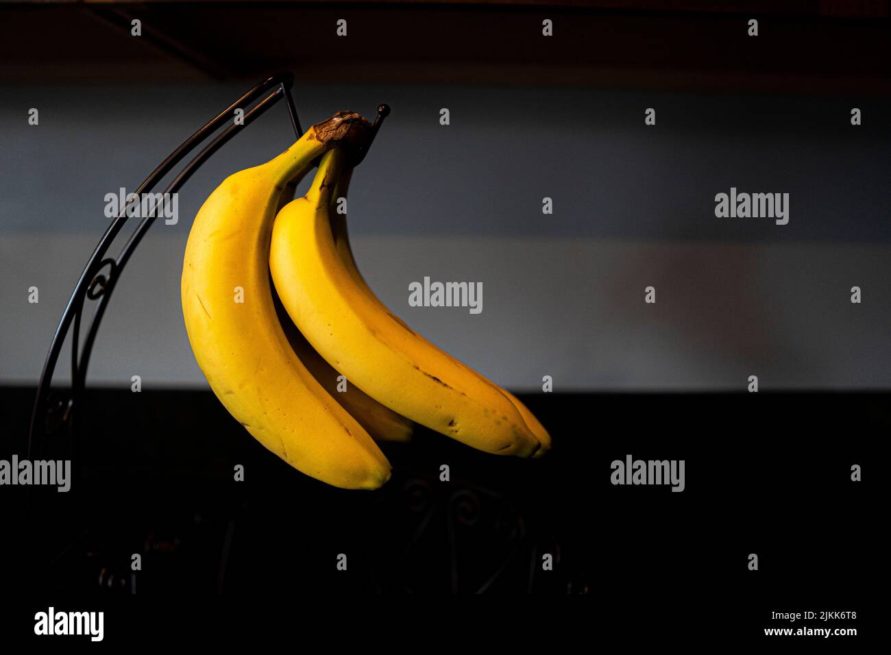 A closeup of bananas hanging on a steel bar in a dark room Stock Photo ...