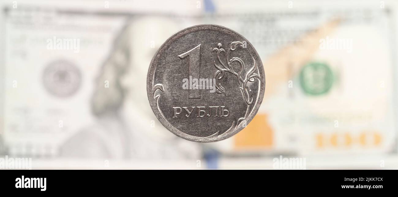 Russian ruble on the background of a blurred one hundred dollars bill ...