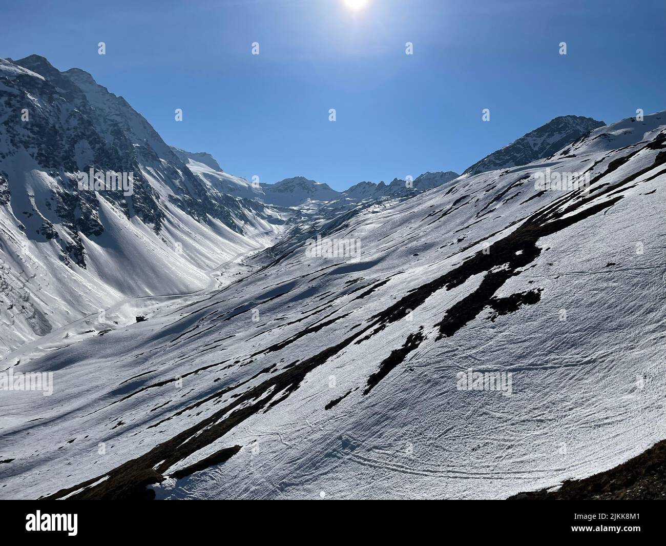 A high mountains covered with snow with a blue sky and the shining sun ...