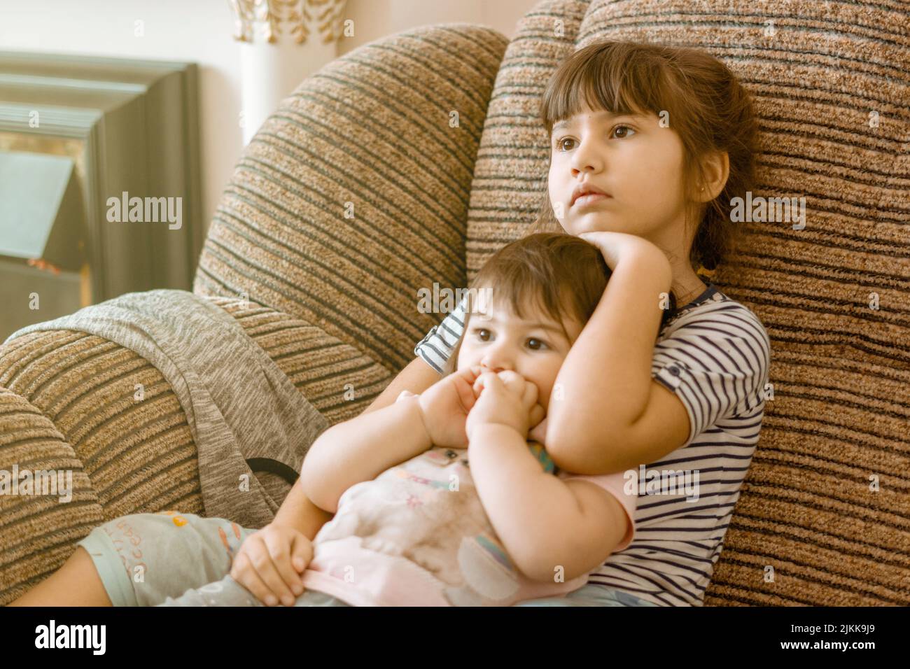 A beautiful shot of an older sister hugging her little sister and ...