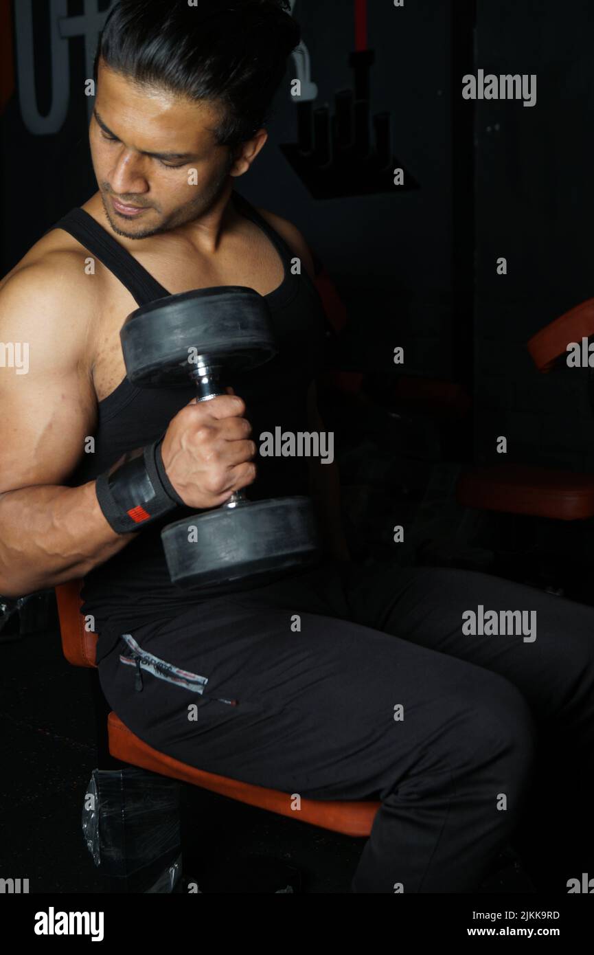 A vertical shot of an Indian young male training with a dumbbell Stock ...