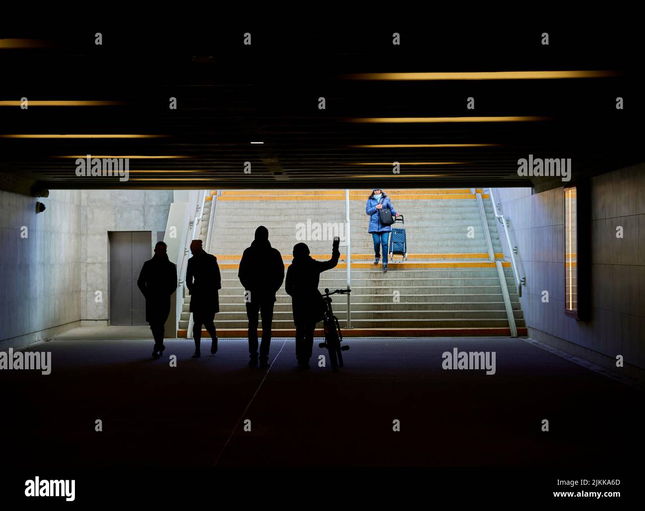 A closeup of People walking in an underground passage leading to stairs ...