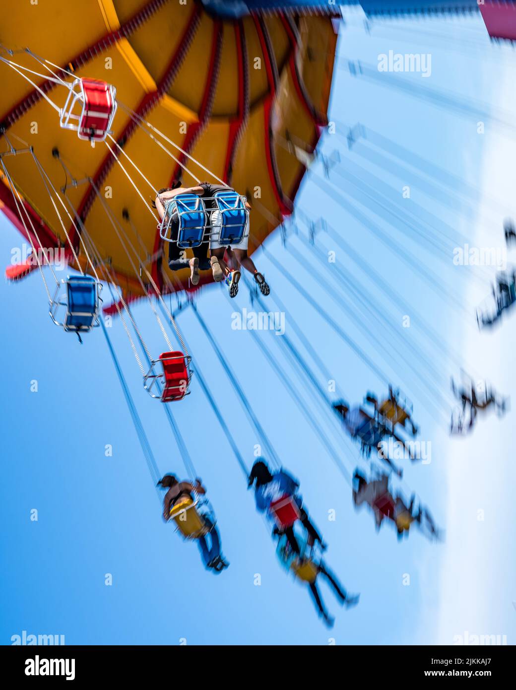 A low angle shot of Fair Flying chairs attraction in background of sky ...