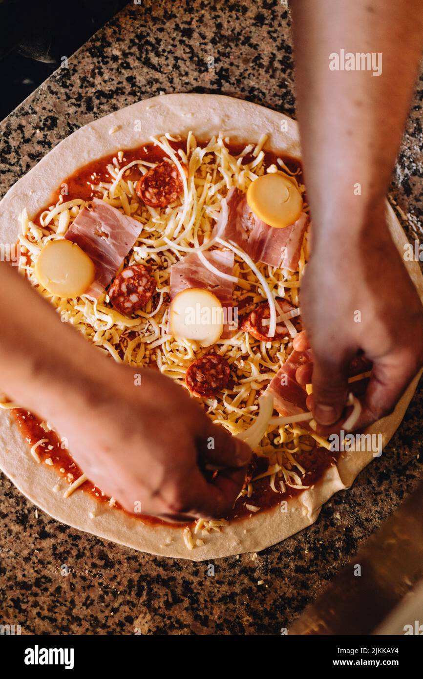 A top view of hands adding cheese and sausage to pizza Stock Photo - Alamy