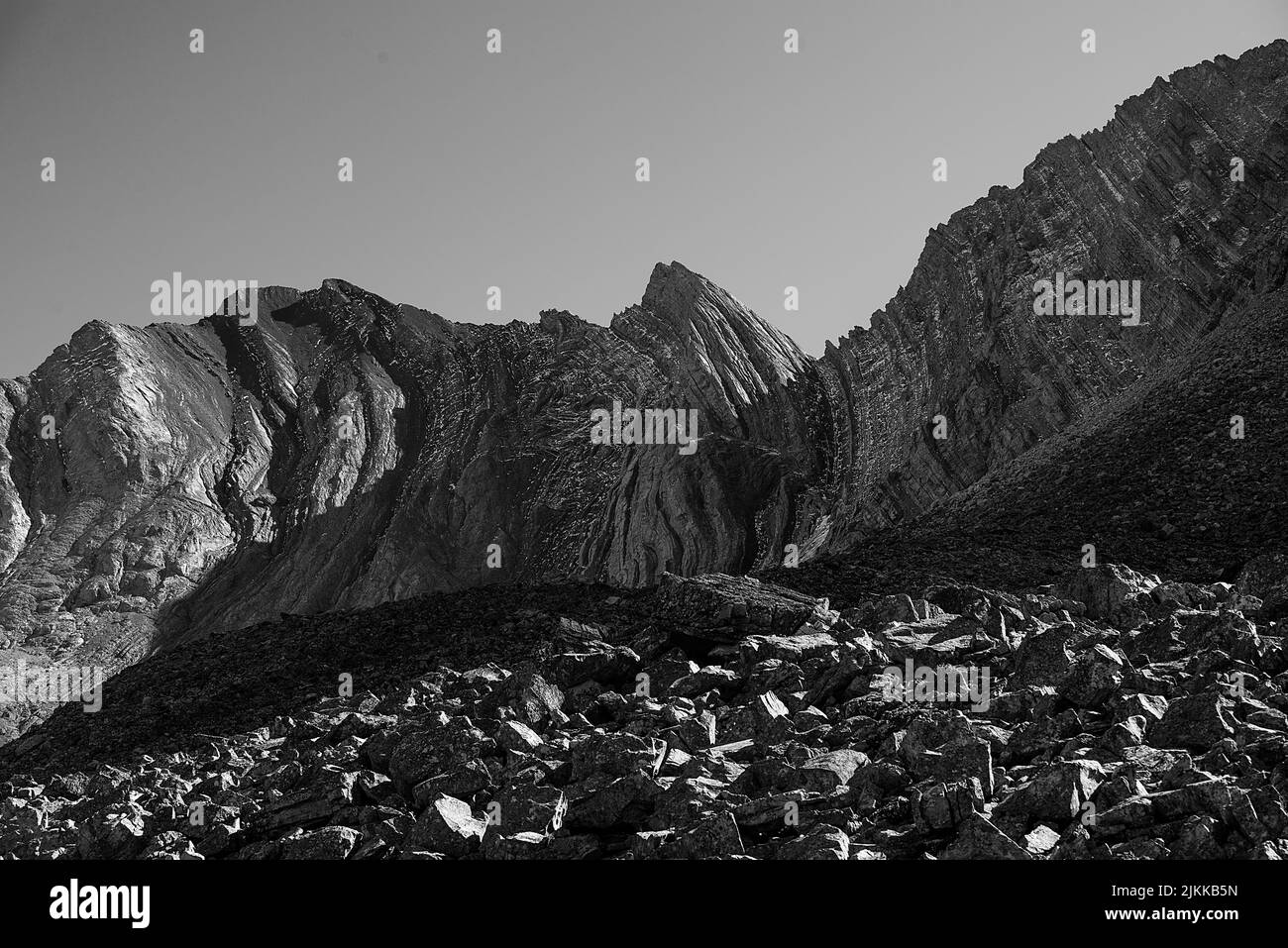 A grayscale low angle shot of big cliffs with rocks at the bottom Stock ...