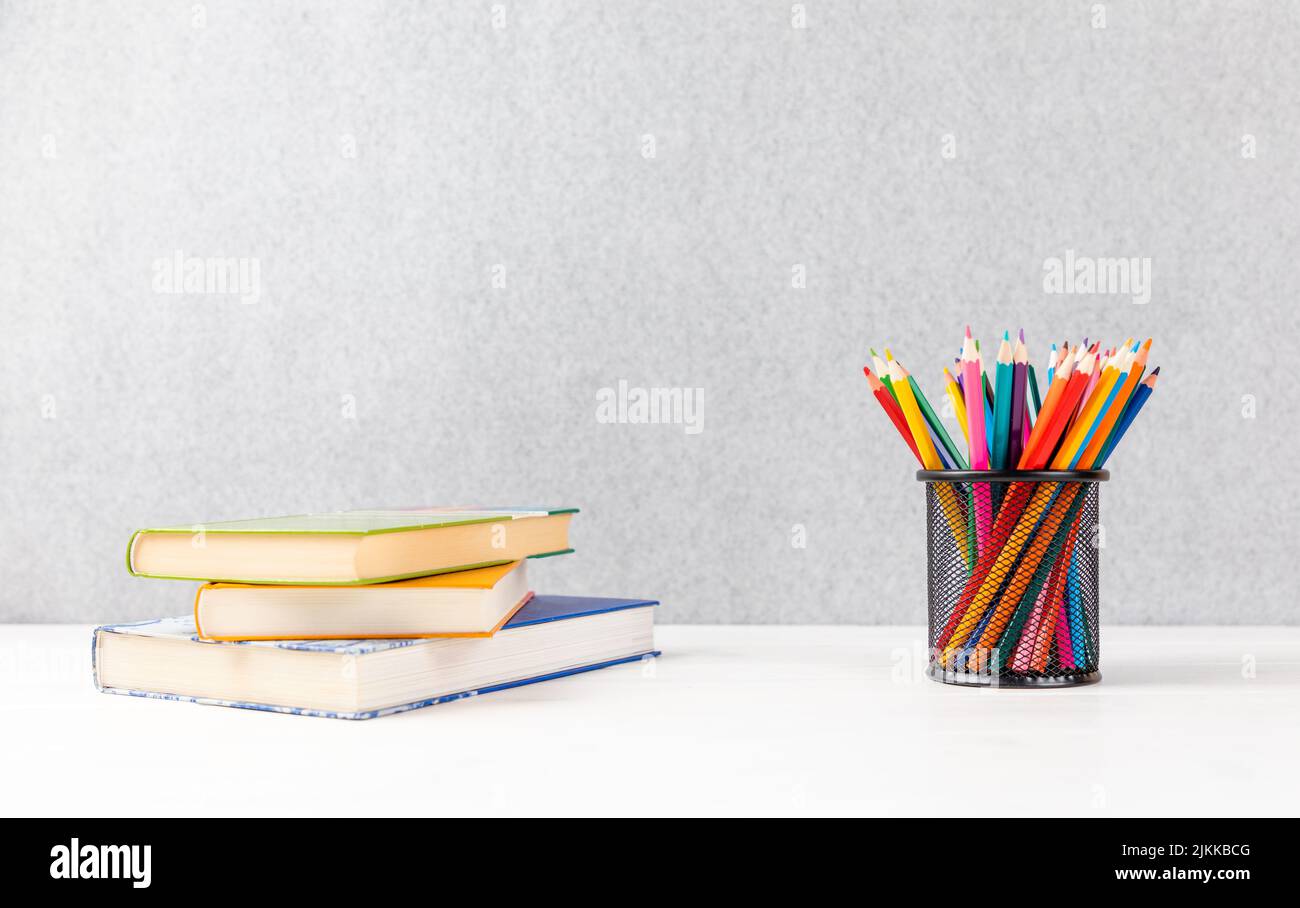 books and colorful pencils on a desk with gray background and copyspace ...