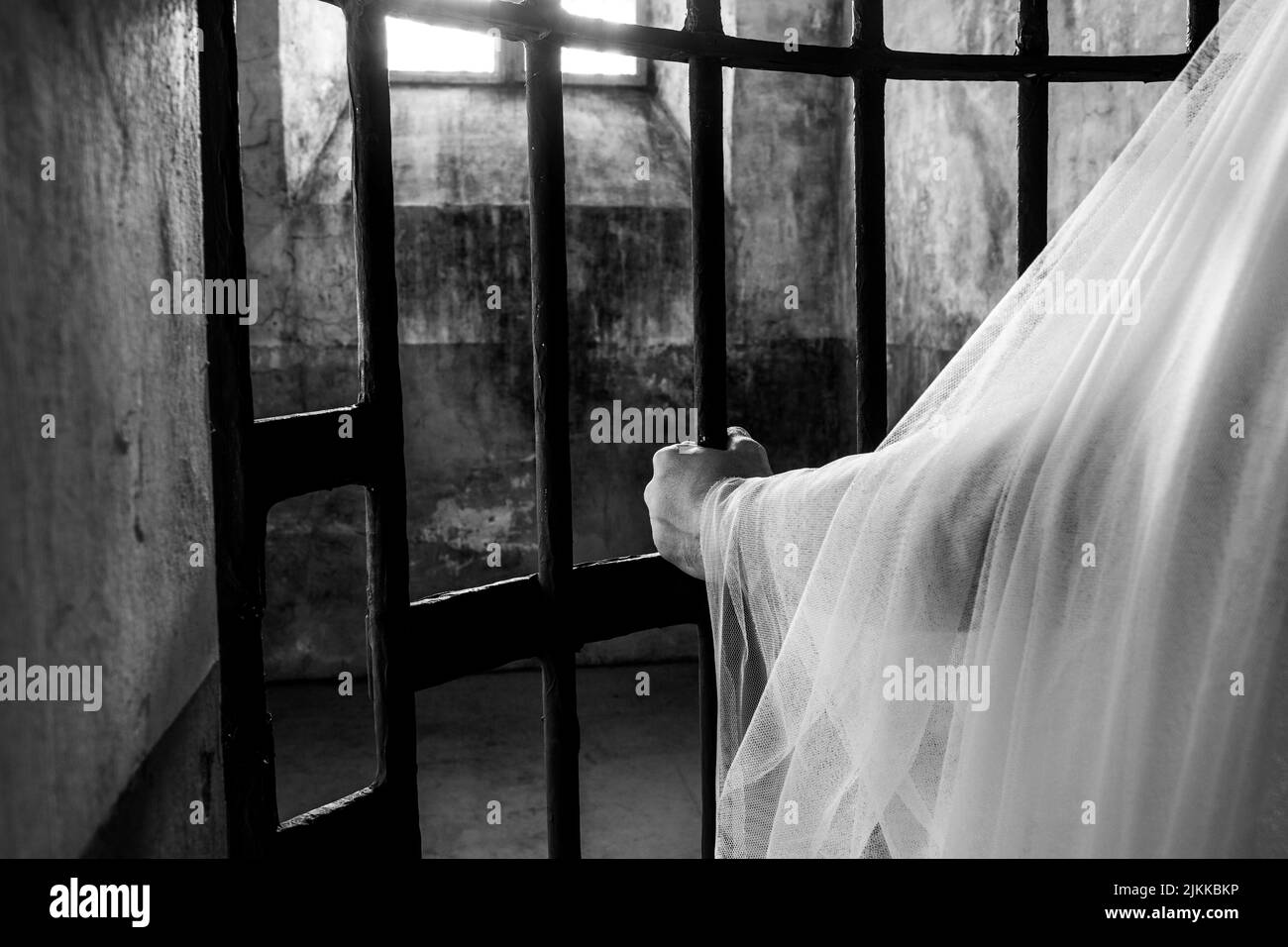 A grayscale shot of a person wearing a bride dress and catching metal ...