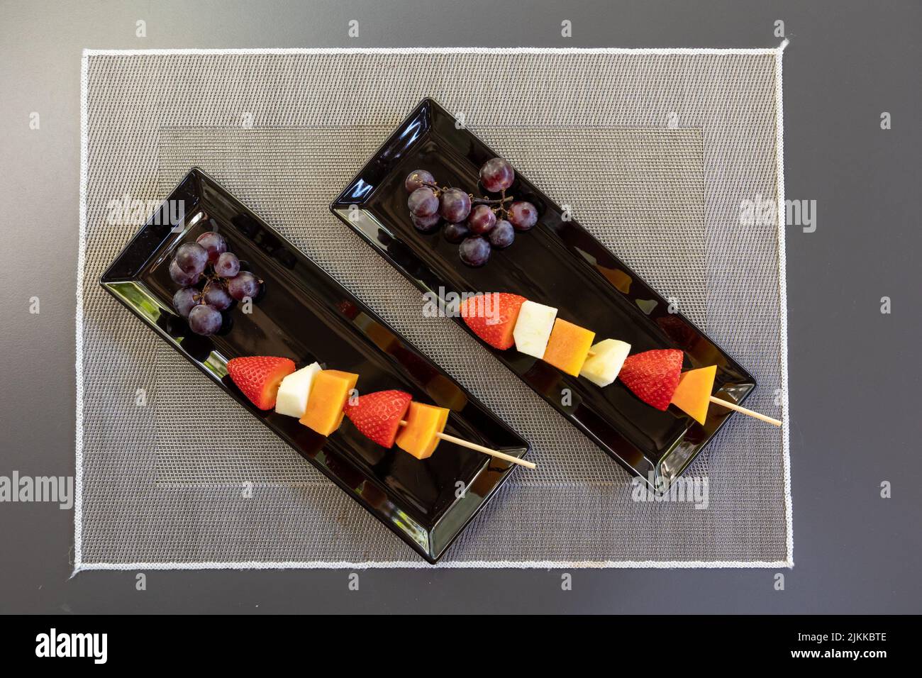 A high-angle shot of some fresh-cut fruits on wooden sticks on ...