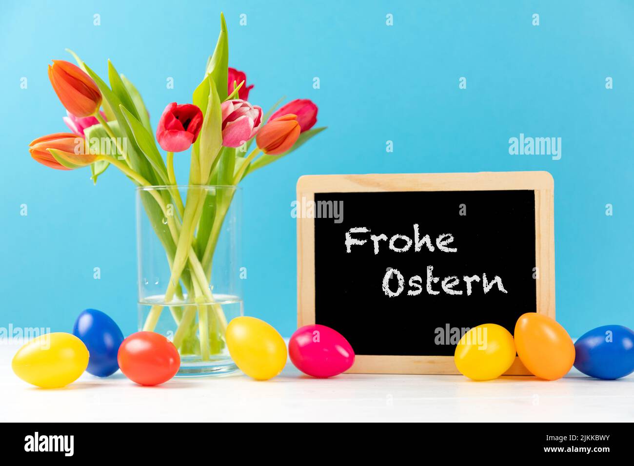 colorful tulips with chalkboard and easter eggs on a blue background ...