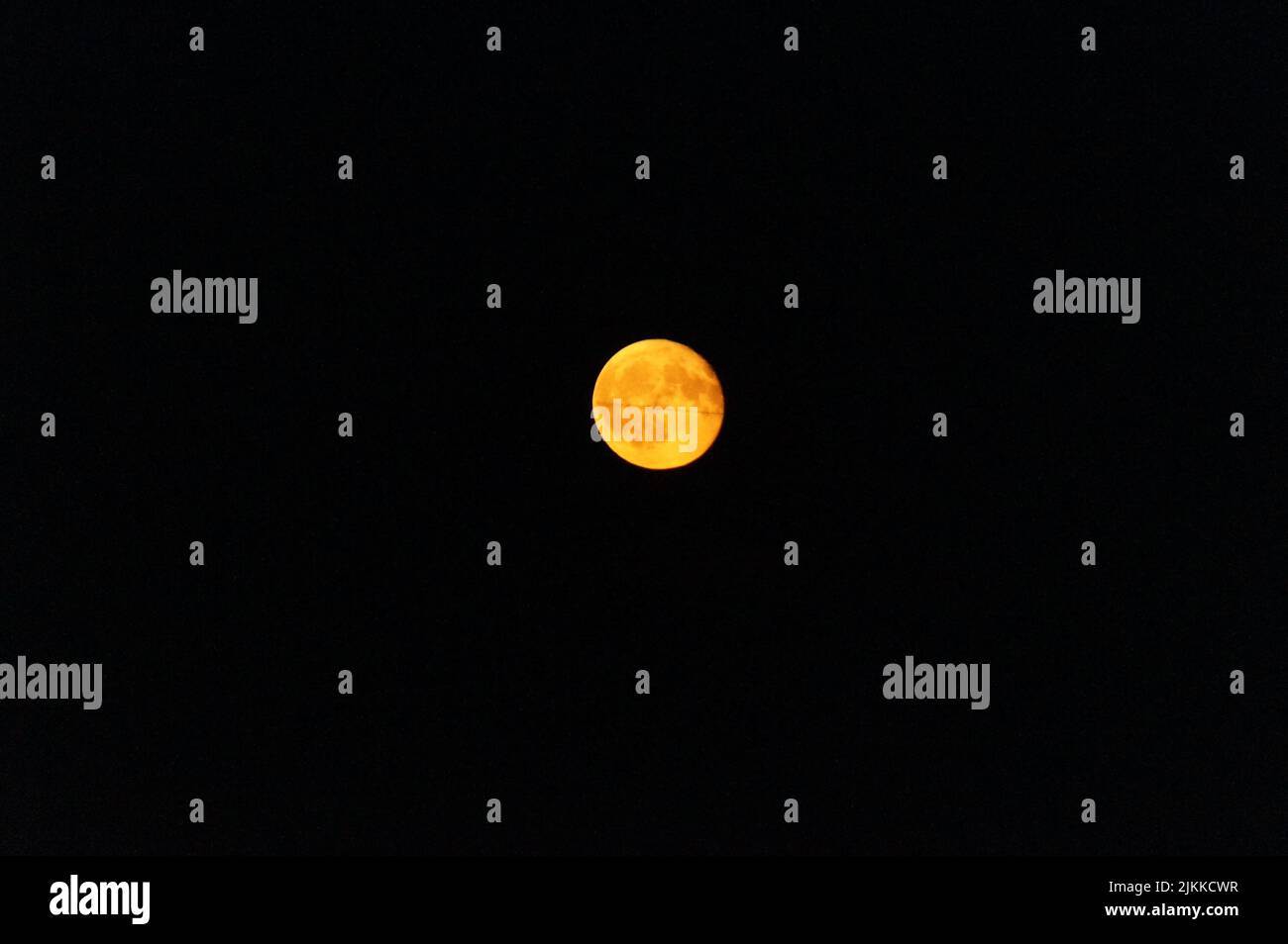 The yellow moon in the dark black sky captured at night Stock Photo - Alamy