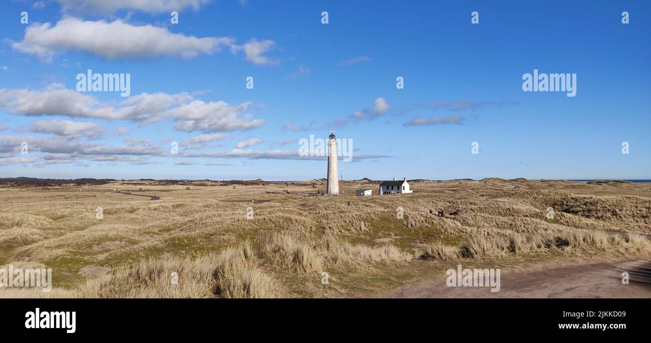 A beautiful view of a lighthouse in dunes against a cloudy sky Stock ...