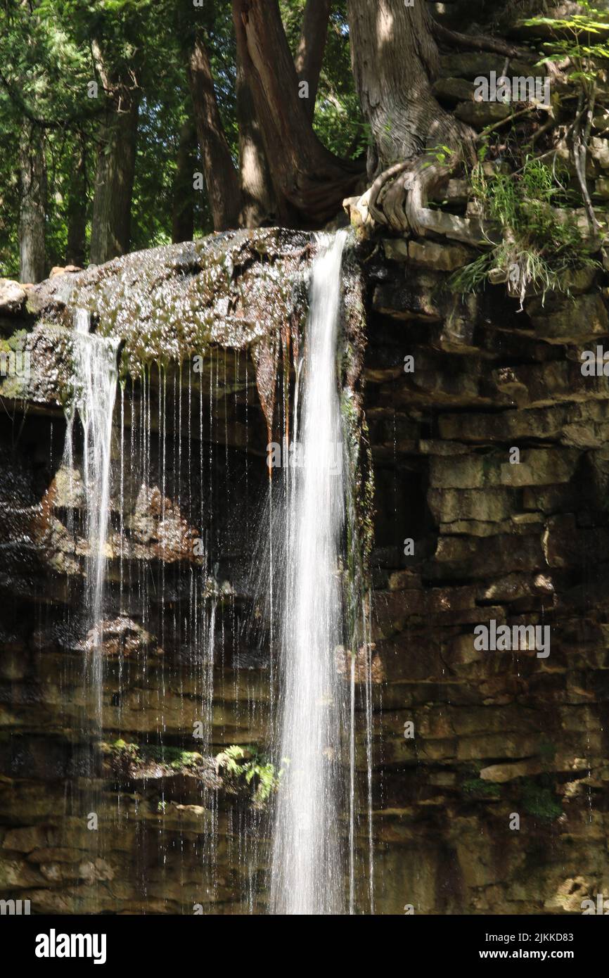 A vertical shot of an artificial waterfall flowing from high rocks in a ...