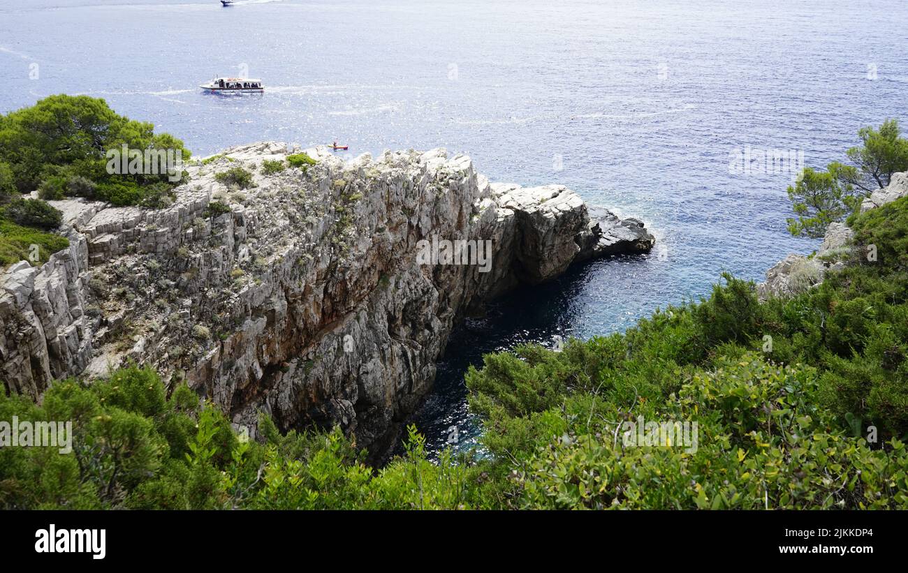 A scenic view of a boat sailing in the blue seascape against the rocky ...
