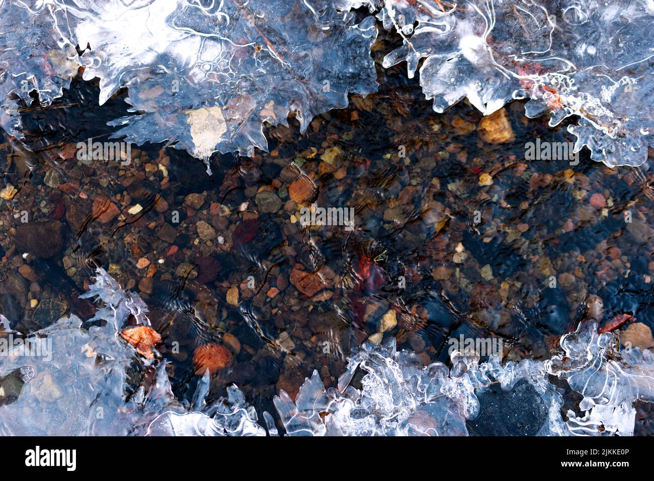 The ice on a frozen river with pebbles underwater Stock Photo - Alamy