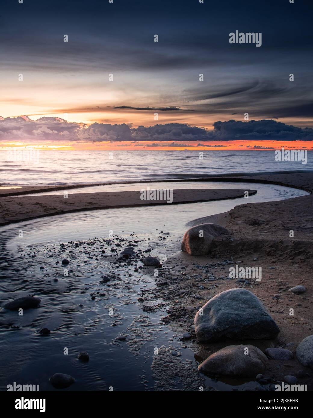 A beautiful view of the sea with many rocks under a cloudy sunset sky ...