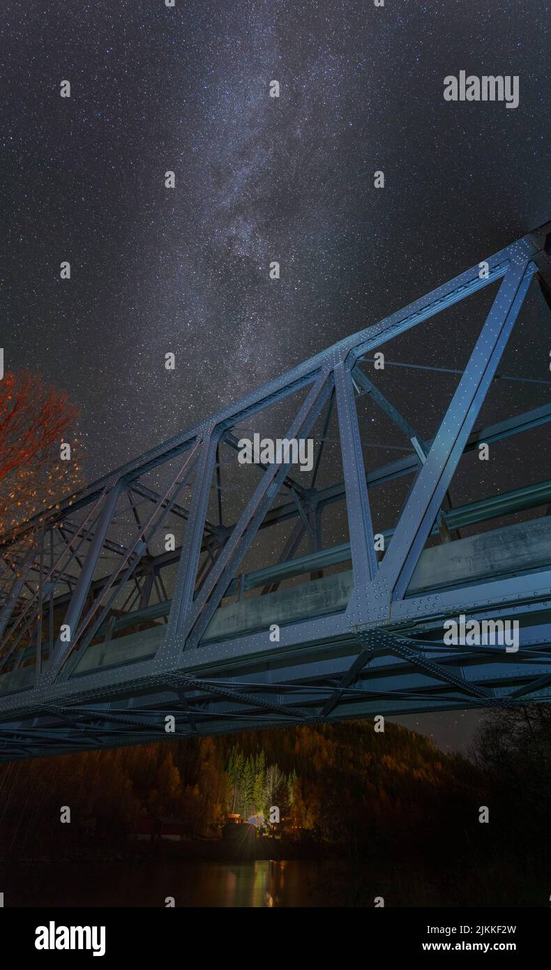 A vertical shot of a metal bridge with a starry night sky in the ...