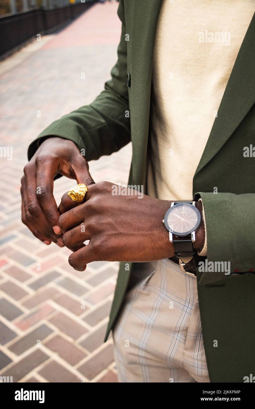 A vertical shot of a modern watch on a man's hand in a green suit ...