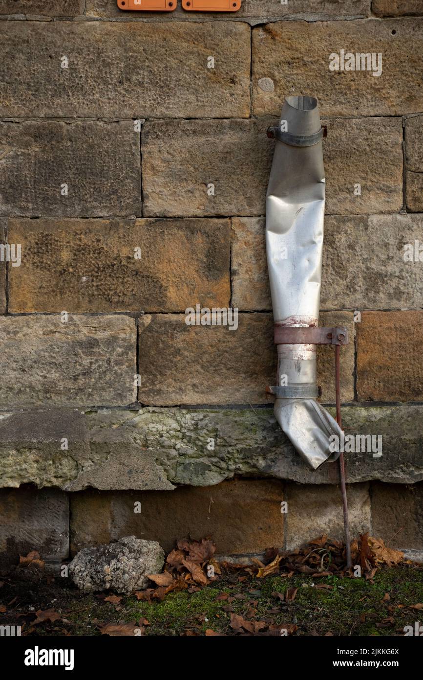 A vertical shot of a broken metallic pipe made for rain water on the ...