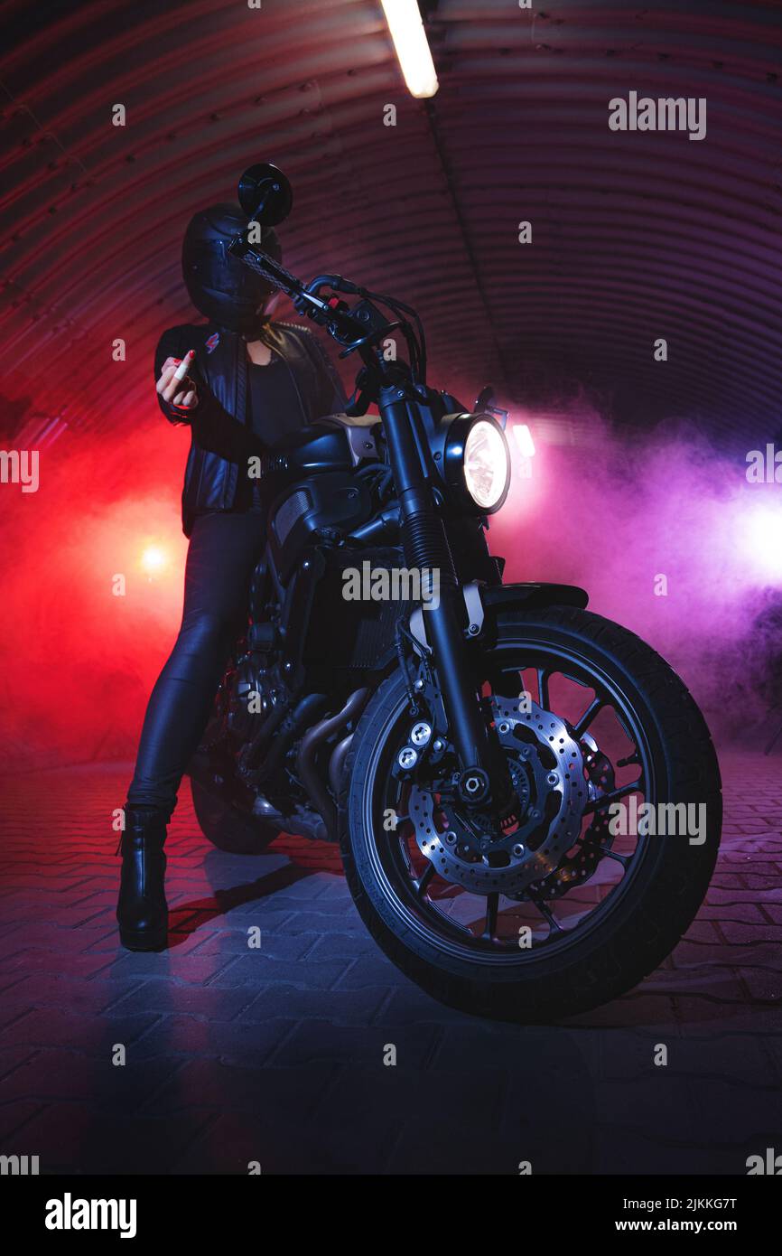 A vertical shot of a female bike in a hangar with colorful smoke and ...