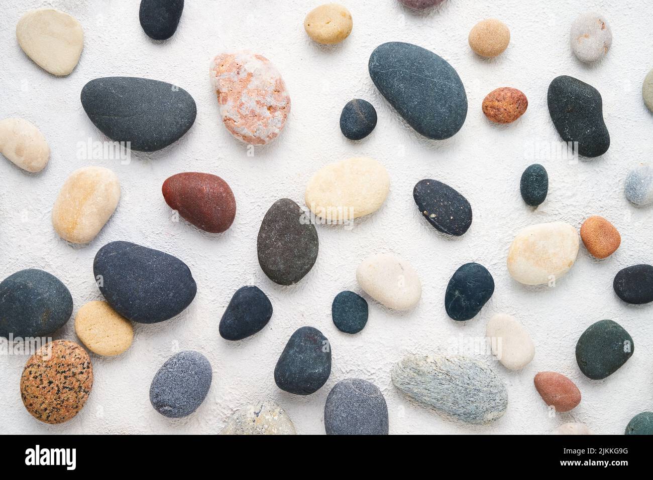 Set of colorful sea stones on white concrete backdrop. Top view ...
