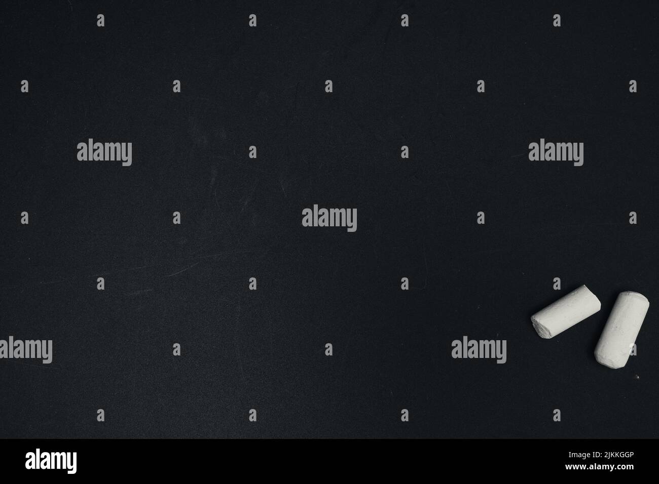A top view of two pieces of white chalk on a blank black surface Stock ...