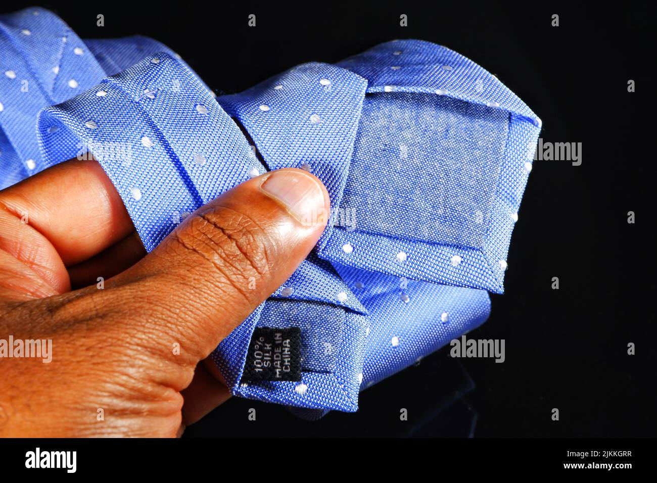 A closeup shot of a male hand showing blue tie with white dots on the ...