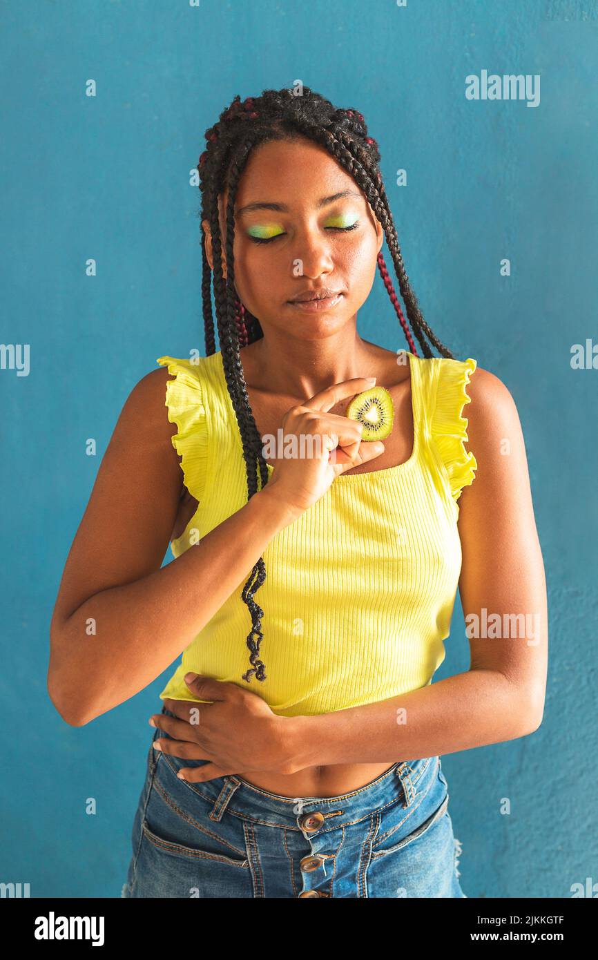 A vertical of a beautiful young mixed race female posing with a kiwi in ...